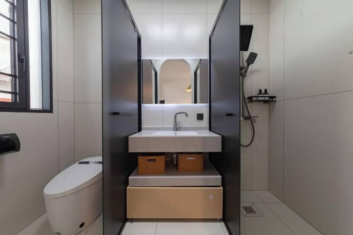 Casa de banho compacta com sanita, lavatório e chuveiro.