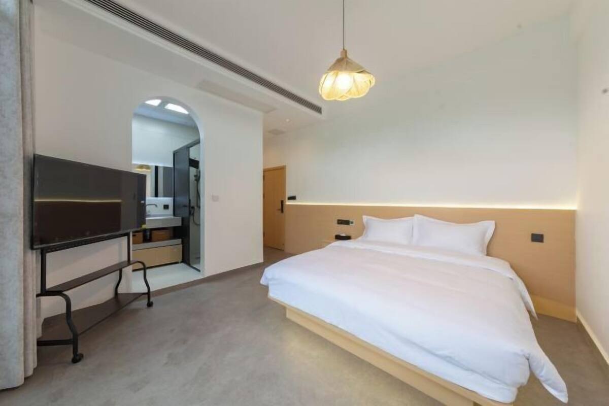 Quarto de hotel moderno com uma cama, uma escrivaninha e uma televisão.