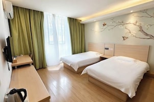 Quarto de hotel com duas camas, uma mesa, uma televisão e uma janela com cortinas.