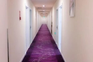Um corredor longo com carpete roxo e paredes brancas.