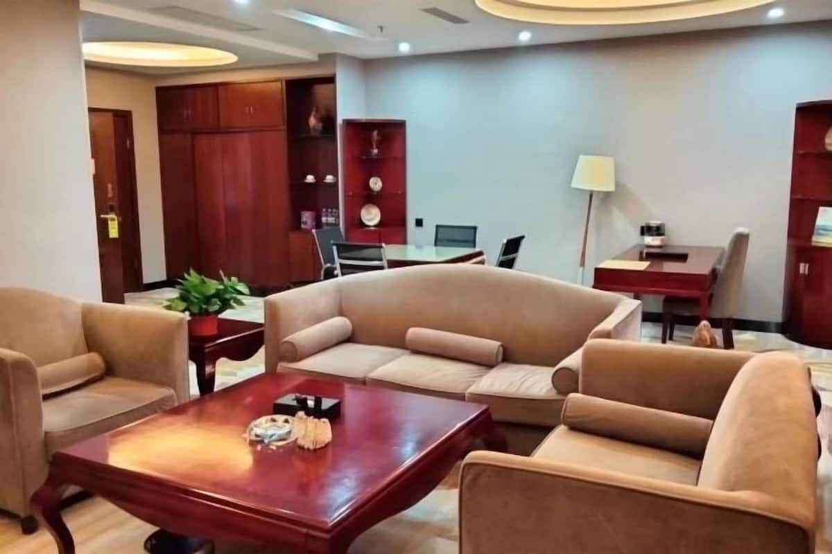 Um saguão moderno de hotel com um conjunto de sofás, uma mesa de centro e uma área de trabalho.