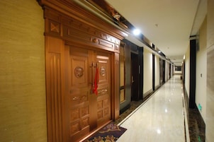 Um corredor com portas de madeira, piso de mármore e tapete na entrada.