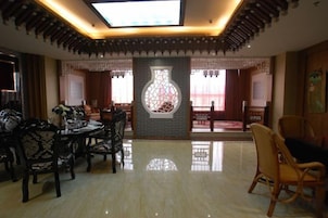 Quarto espaçoso com área de jantar, um vaso decorativo grande e vista pela janela.