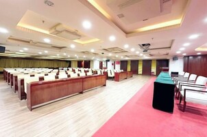 Uma sala de conferência com mesas e cadeiras dispostas em fileiras, um pódio e um palco.