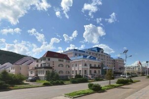 Um hotel com várias andares e telhado vermelho, cercado por vegetação e céu claro.