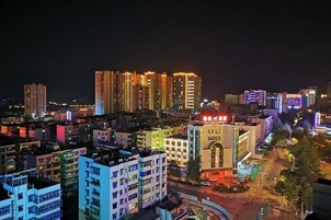 Paisagem urbana noturna com arranha-céus e um hotel bem iluminado.