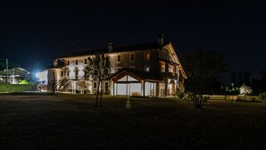 Uma casa grande, com vários andares, um alpendre bem iluminado e uma garagem.