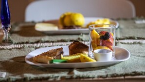 Uma mesa com um prato de comida que inclui um pastel, um copo com fruta e uma pequena tigela de molho.