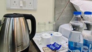 Uma bancada de cozinha com chaleira, xícaras, um tabuleiro com saquinhos de chá e garrafas de água.