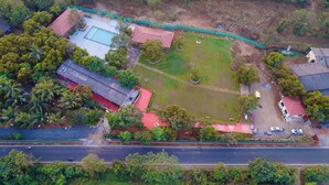 Vista aérea de uma propriedade com piscina, quadra de tênis e vegetação ao redor.