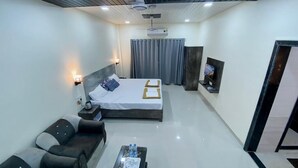 Quarto de hotel moderno com cama, sofá, mesa de centro e televisão.