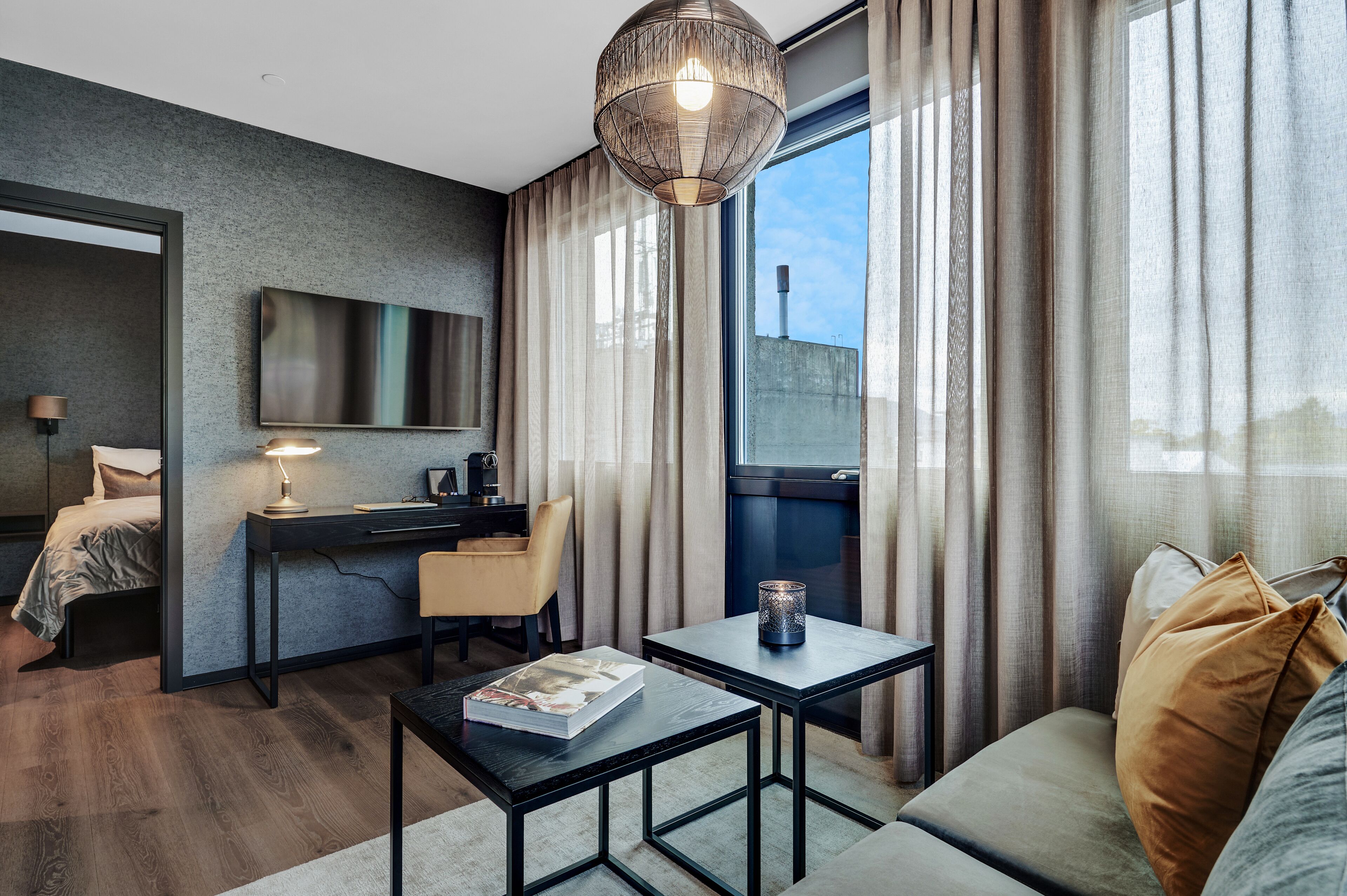 Quarto de hotel moderno com cama, escrivaninha e área de estar.