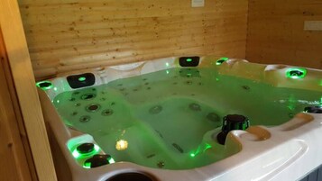 Uma banheira de hidromassagem com vários jatos, iluminação verde e interior de madeira.