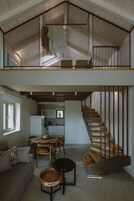 Interior estilo loft com mezanino, cozinha aberta e escada.