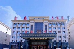 Um hotel com vários andares, entrada destacada e sinalização.