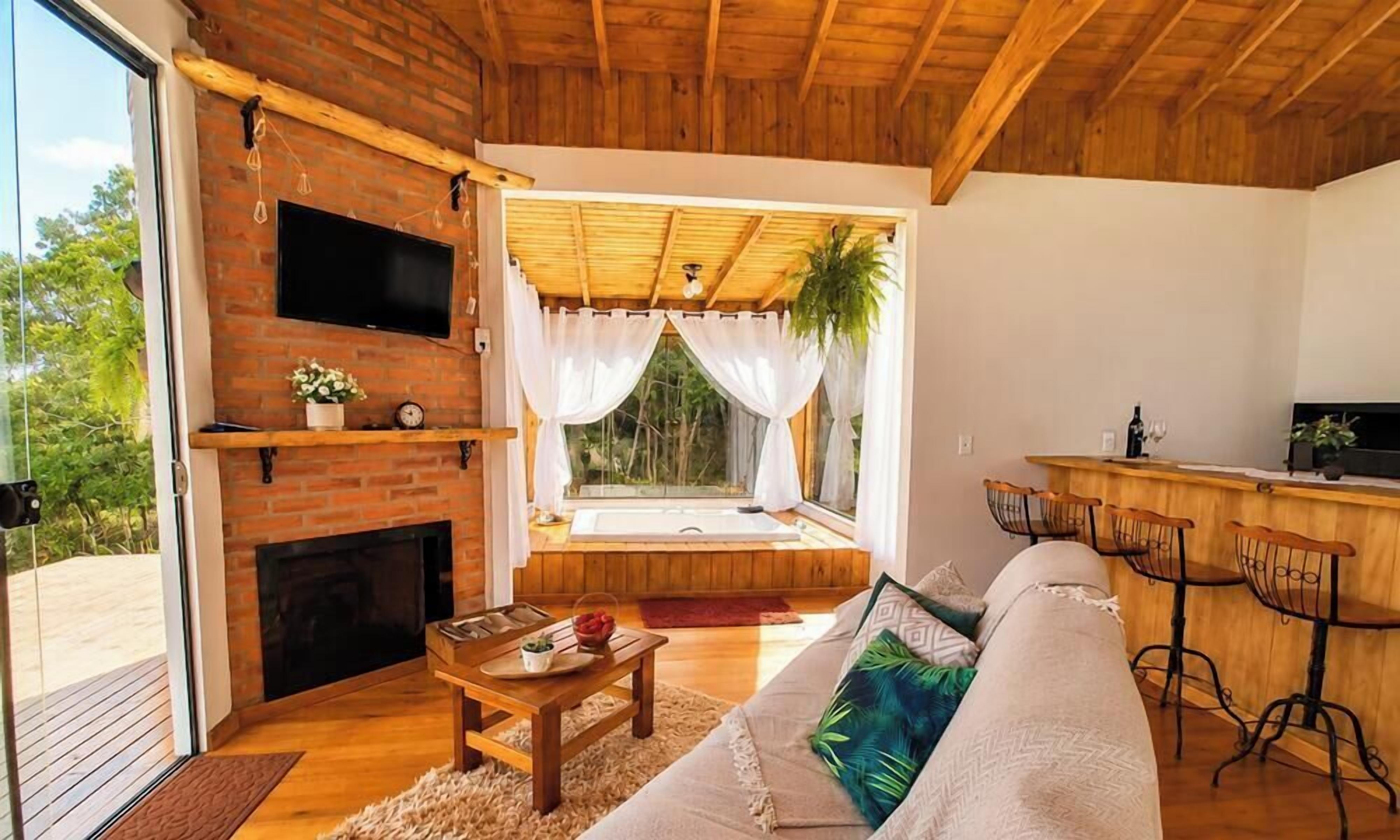 Uma sala de estar acolhedora, com lareira, televisão, sofá e um espaço bar com banquetas.