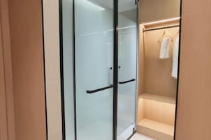 Um banheiro moderno com box de vidro, porta-toalhas e um banco embutido.