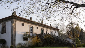 Um edifício histórico com fachada simétrica, janelas em arco e entrada central.