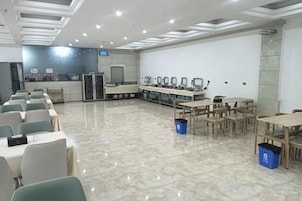 Uma sala de conferências com uma mesa comprida, cadeiras e uma tela de projetor.
