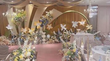 Um espaço para eventos decorado com arranjos florais, tapete rosa e um candelabro.