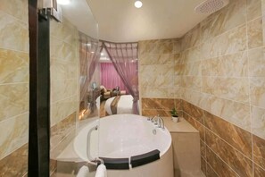 Casa de banho com uma banheira grande, zona de duche e toucador com espelho.