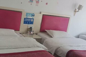 Quarto de hotel com duas camas, uma mesa de cabeceira com telefone e máquina de café, e uma luminária fixada na parede.