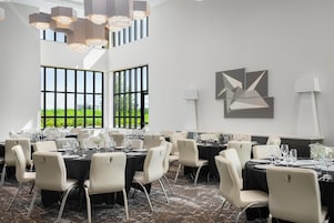 Uma sala de conferência com várias mesas, cadeiras e luminárias modernas.