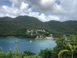 Uma vila costeira com edifícios numa encosta, com vista para uma baía azul-turquesa.