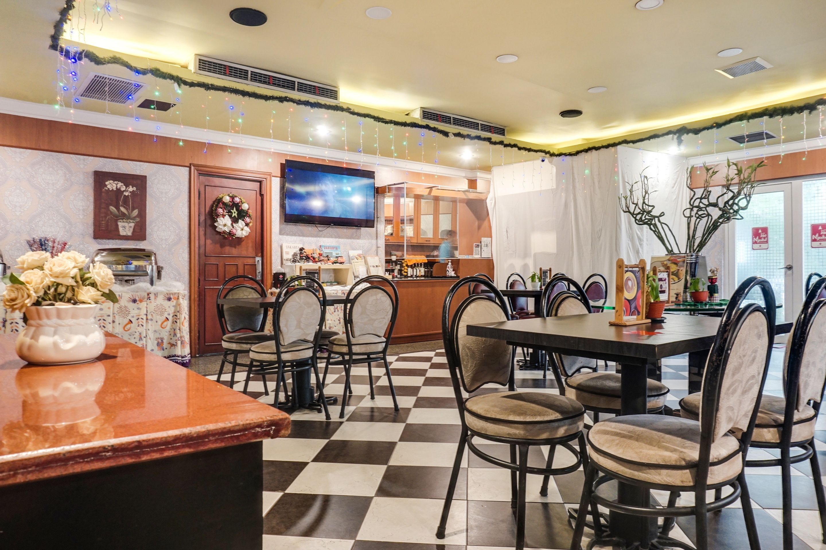 Um restaurante com chão xadrez, balcão de madeira e televisão na parede.