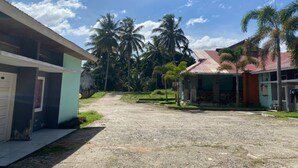 Zona residencial com calçada de cascalho, casas com telhados vermelhos e palmeiras.