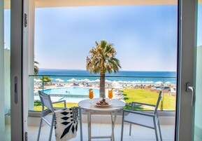 Varanda com mesa, cadeiras e vista para a praia e piscina.