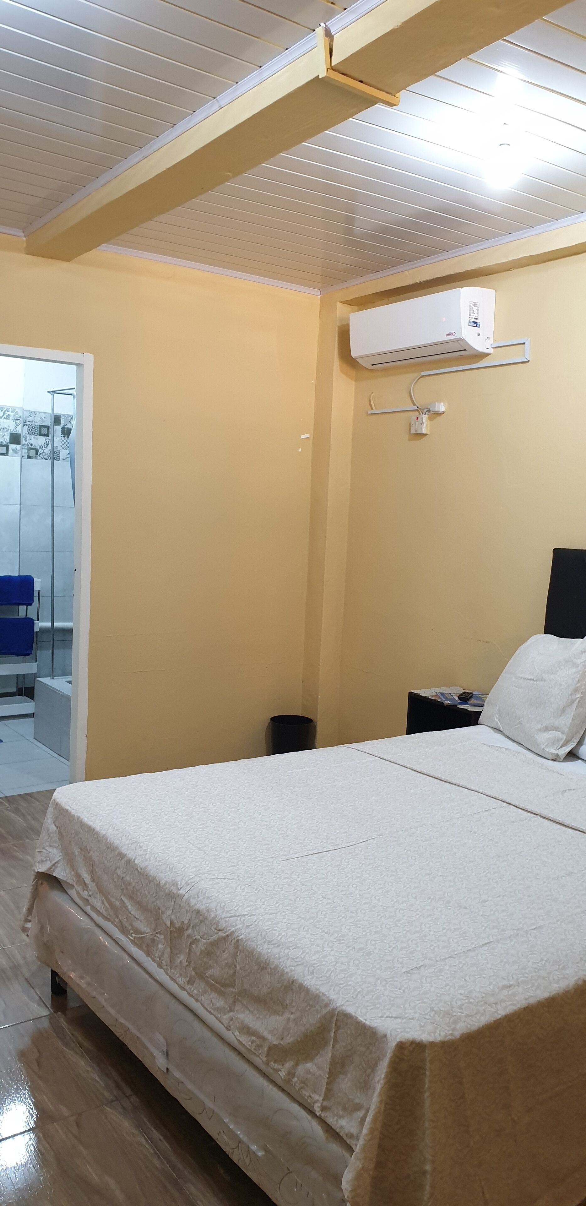 Quarto de hotel com cama, mesa de cabeceira, ar condicionado e janela.