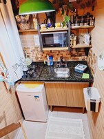 Uma cozinha compacta com micro-ondas, pia e pequeno frigorífico.