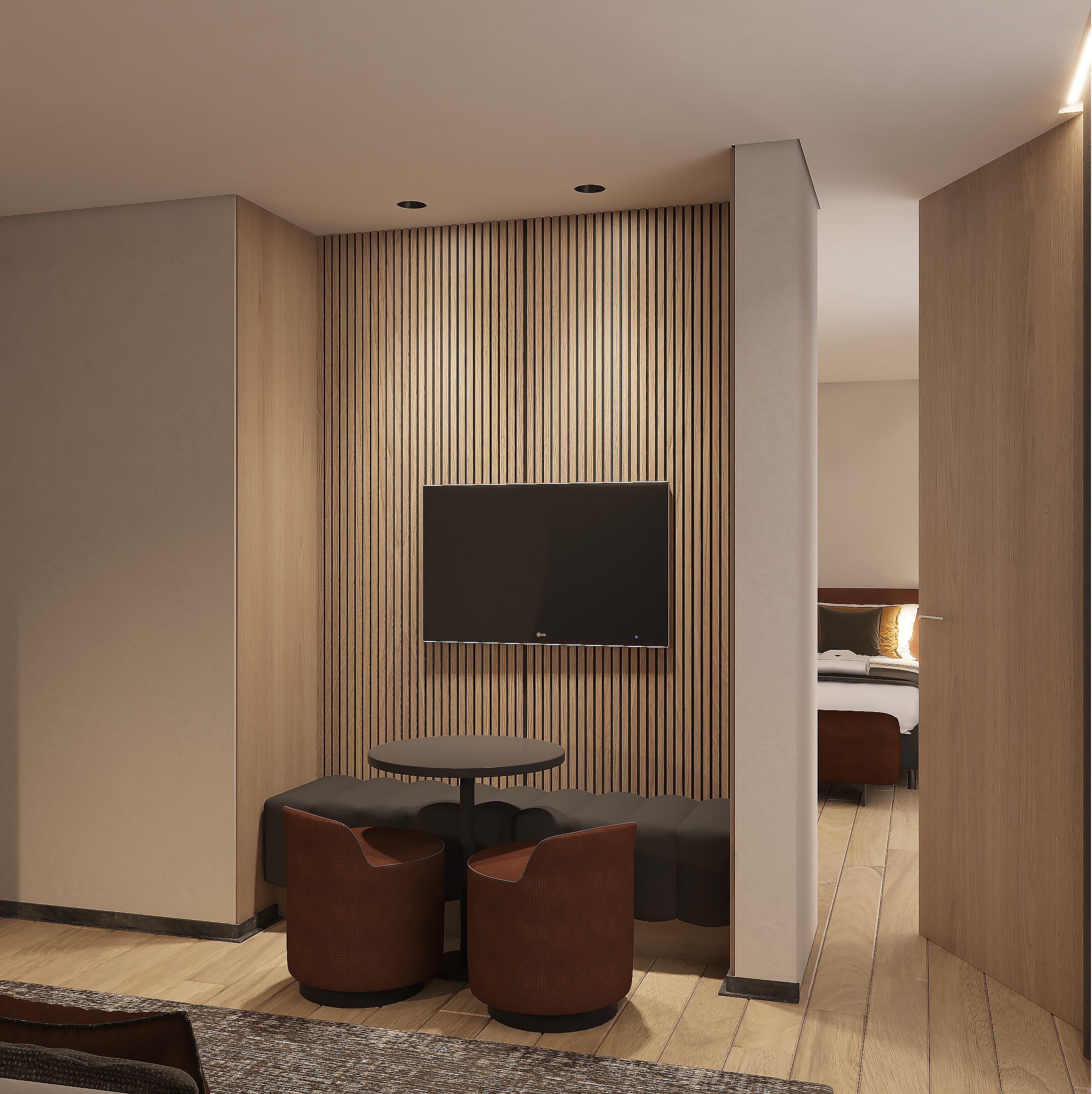 Quarto de hotel moderno com televisão de tela plana fixada em uma parede revestida de madeira, uma mesa redonda com duas cadeiras marrons e uma cama com cabeceira de madeira ao fundo.