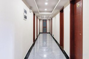 Um corredor comprido e estreito com piso lustroso, portas de madeira e iluminação embutida.