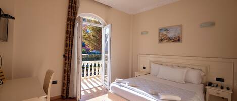 Quarto com cama, mesa de cabeceira, cadeira e porta aberta para uma varanda.