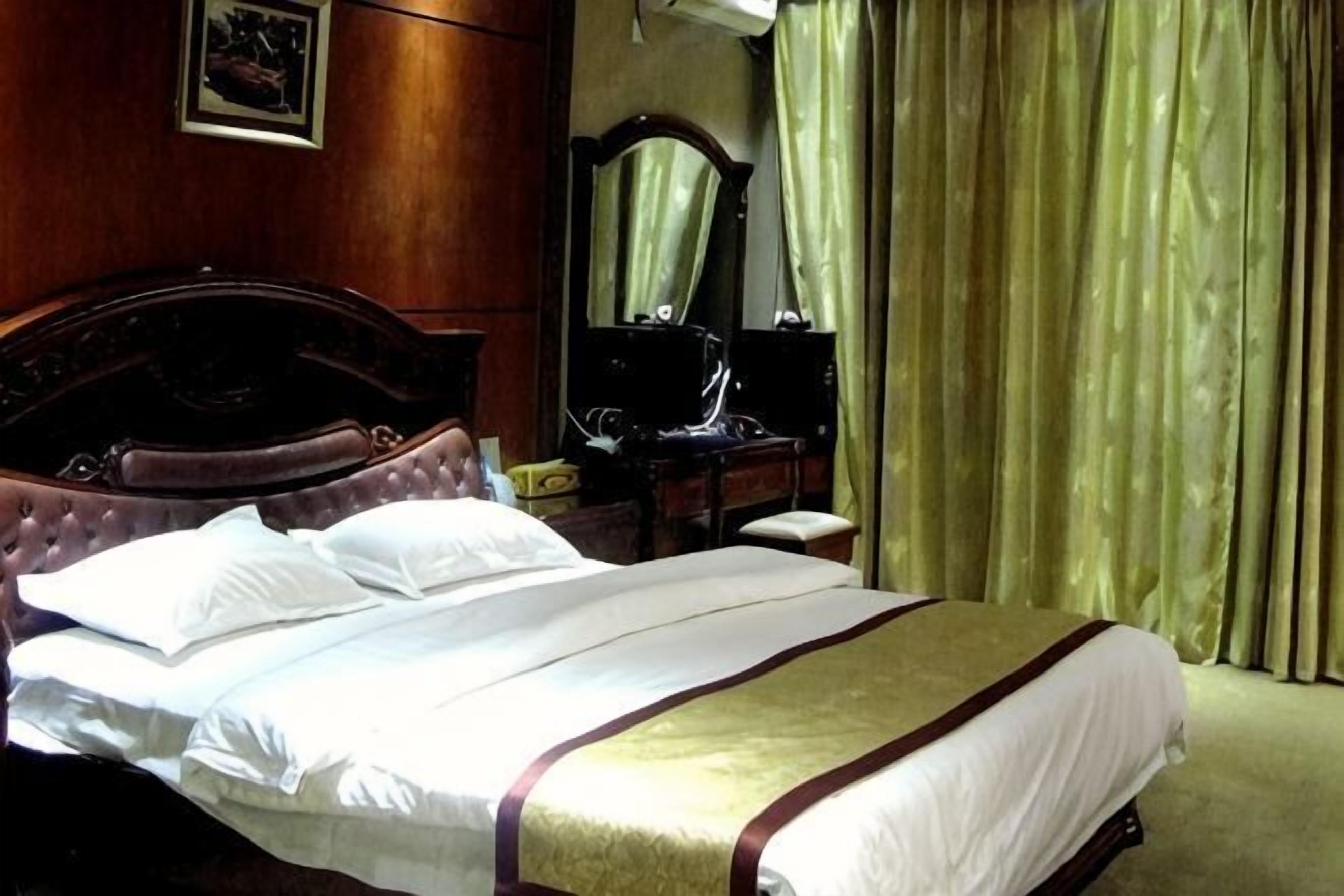 Uma cama bem arrumada com cabeceira, mesa de cabeceira com abajur e espelho na parede.
