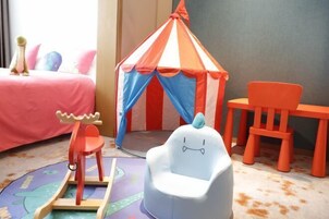 Uma área de recreação infantil com uma tenda, uma cadeira de balanço e uma mesa pequena.