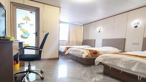 Quarto de hotel com duas camas, uma escrivaninha com cadeira e uma janela com cortinas.