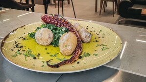 Uma área de refeições com mesas e cadeiras, um prato de comida e um design de interiores moderno.