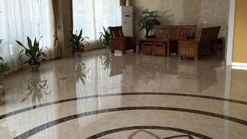 Um hall com piso lustroso, mobiliário de madeira e plantas em vasos.
