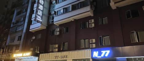 Um edifício com vários andares, com uma fachada visível identificada como 'N77' e outra com a placa 'YAMADA HOTEL'.