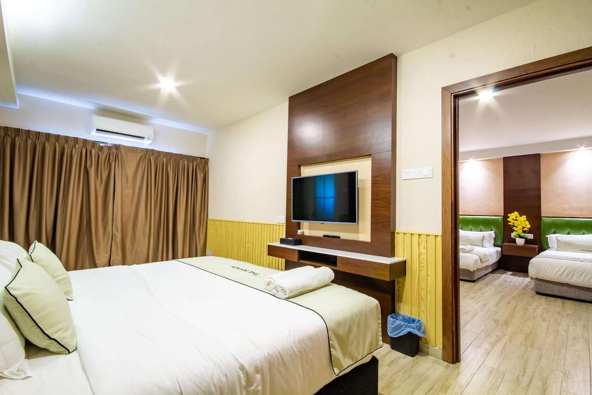 Quarto de hotel com uma cama grande, televisão, escrivaninha e uma cama extra.