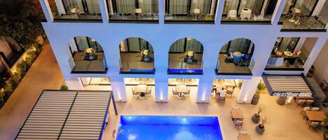 Hotel com várias varandas, piscina central e áreas de estar ao ar livre.