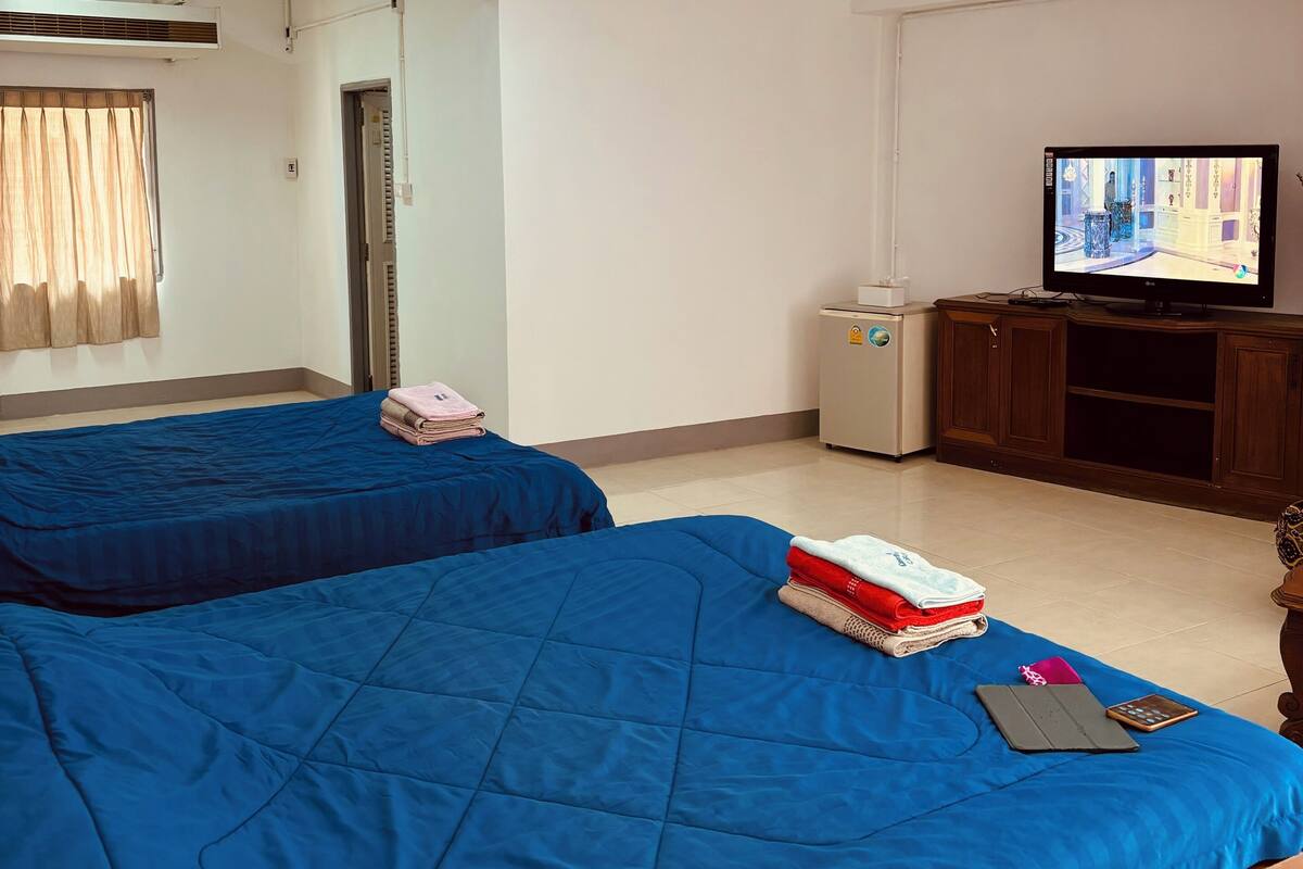 Quarto de hotel com duas camas, televisão, escrivaninha e guarda-roupa.