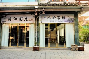 Um hotel com grandes portas de vidro e uma placa que diz 'SHUATHE HOTEL'.