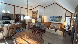 Uma sala ampla com uma mesa de jantar de madeira, um sofá e uma lareira.