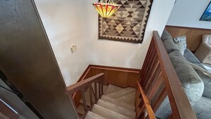 Uma escada de madeira com corrimão que leva a uma sala de estar.
