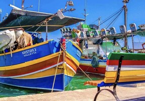 Um porto com várias embarcações coloridas atracadas, incluindo uma chamada 'KRISTURE 1 VALLETTA'.