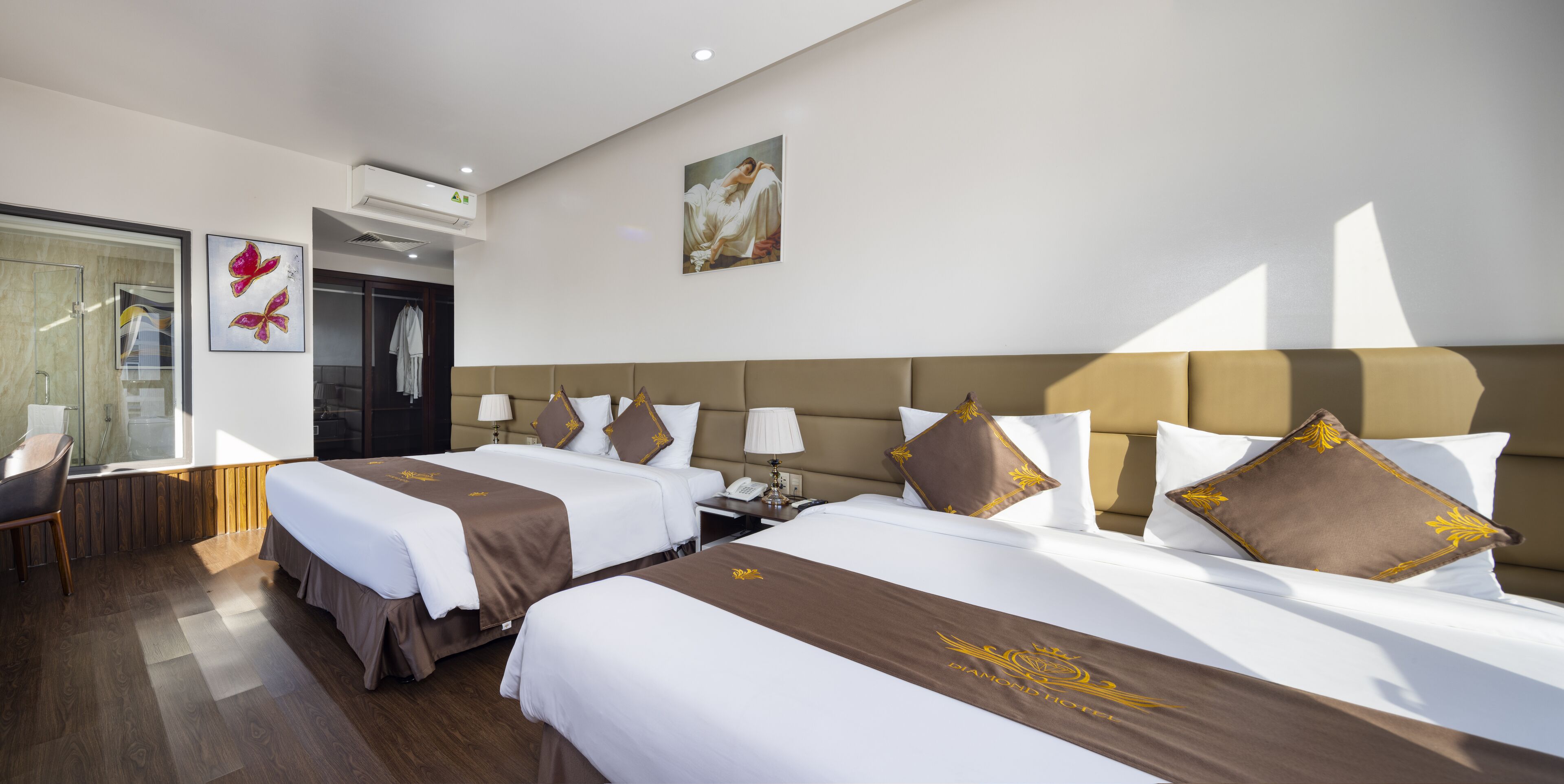 Quarto de hotel com duas camas, um espaço de estar e banheiro.
